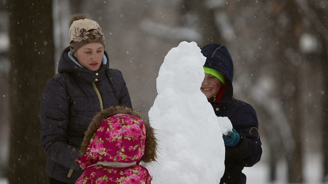 Family builds a snowman in the snow - Free Stock Video