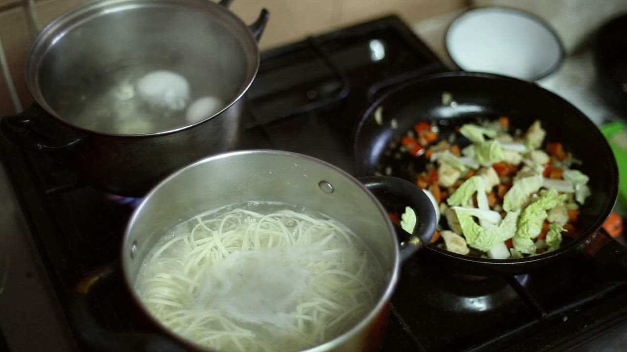Noodles and vegetables cooking on a stove top - Free Stock Video