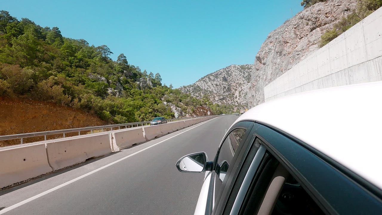 VIew out of a car window driving beside a mountain - Free Stock Video