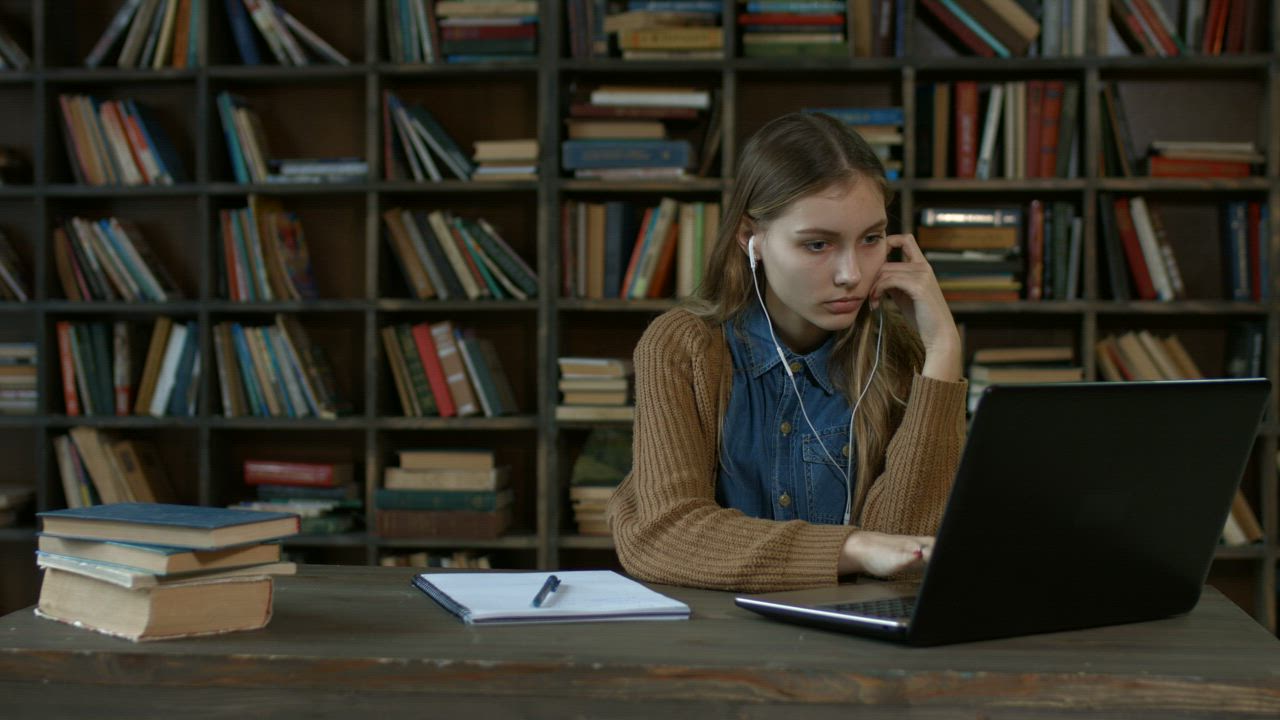 Girl doing homework in a library - Free Stock Video