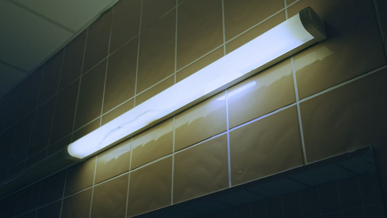 Fluorescent bar light illuminates against tiles - Free Stock Video