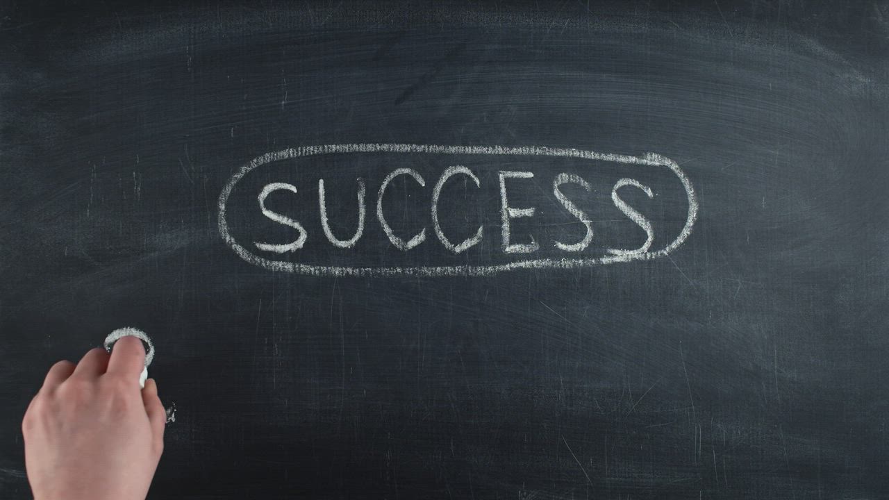 Hand writes 'success' on a blackboard with chalk - Free Stock Video