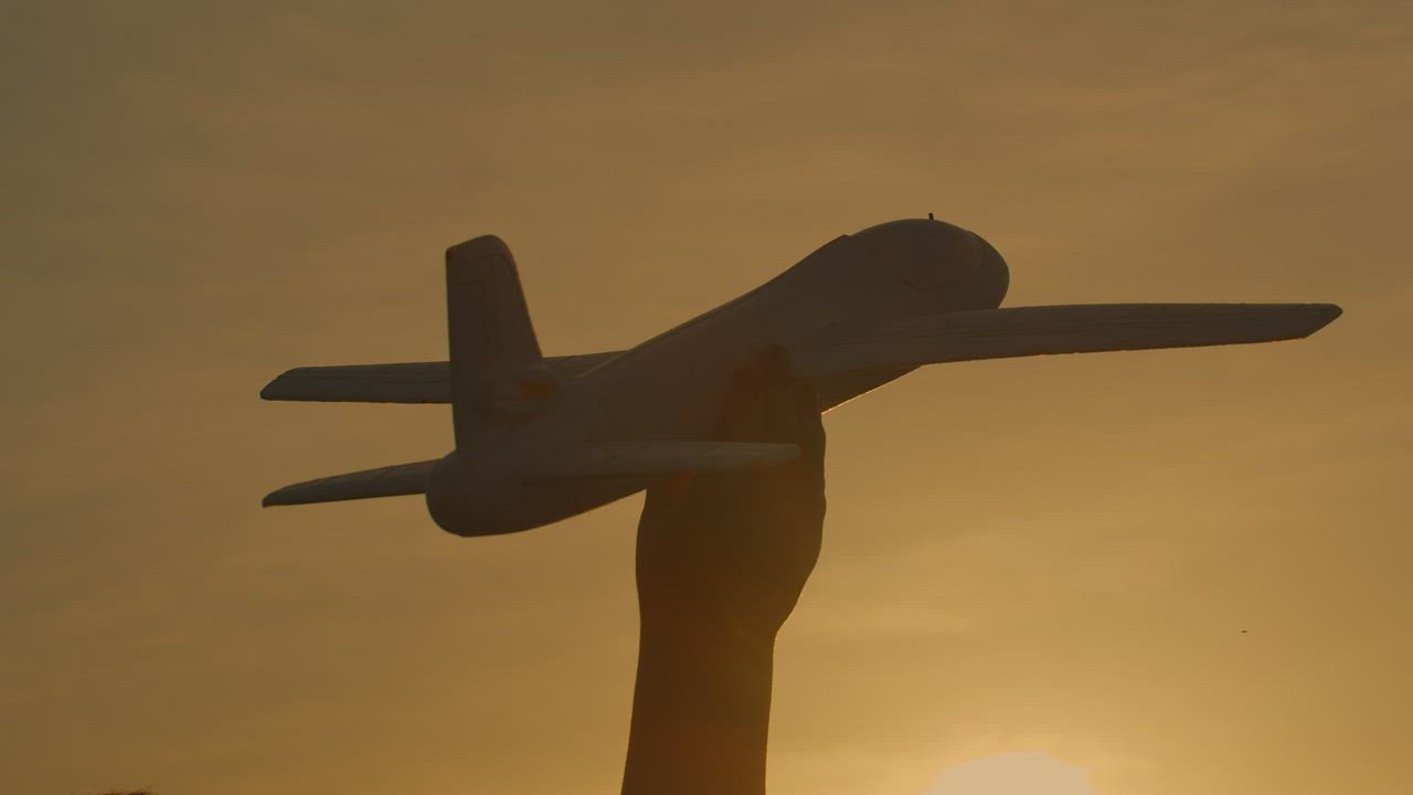 Toy plane being thrown through the air at sunset - Free Stock Video