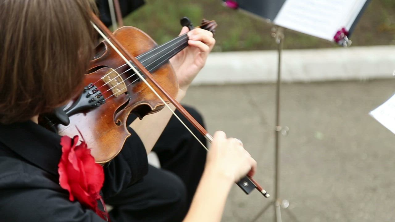 A violinist performing outside with an orchestra - Free Stock Video