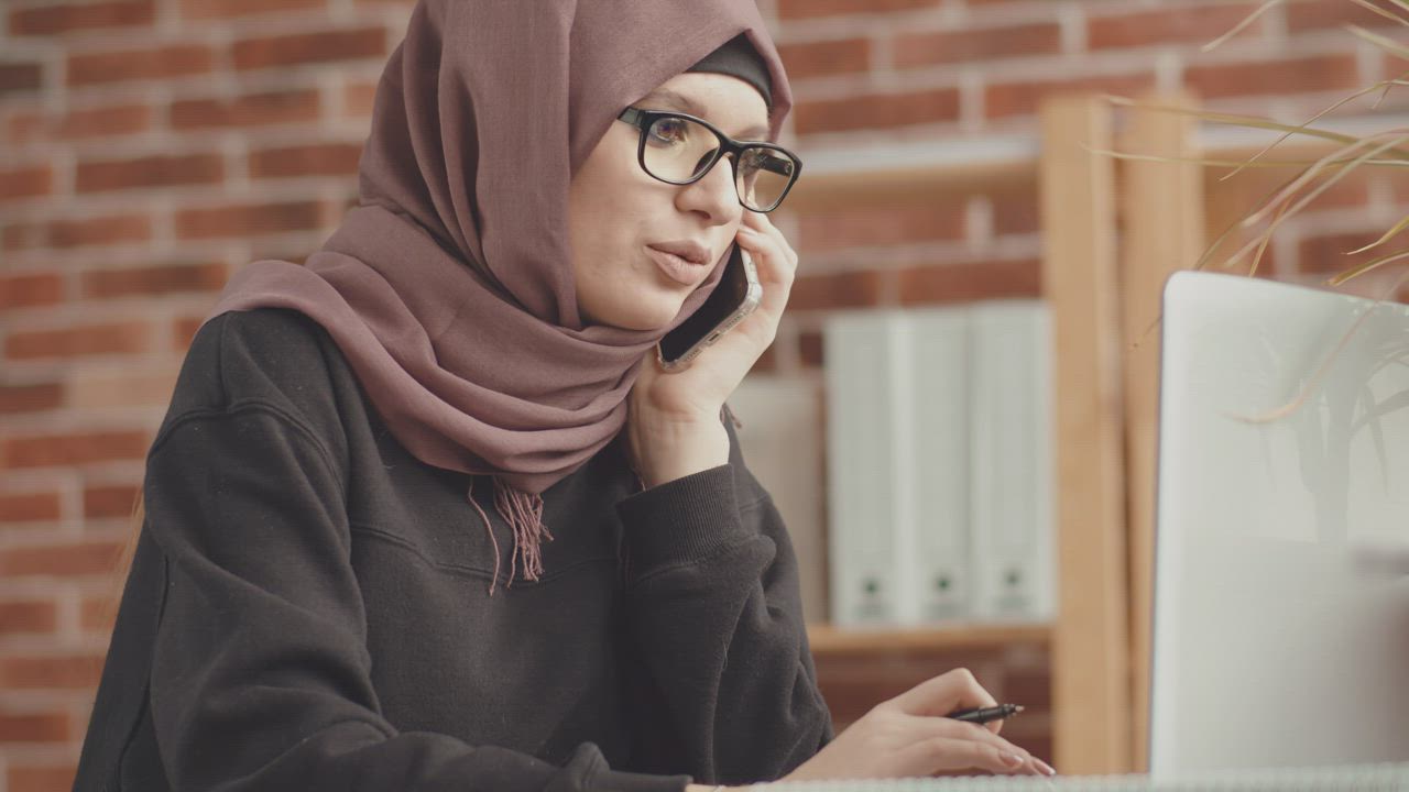 Office worker having a phone call while on their laptop - Free Stock Video