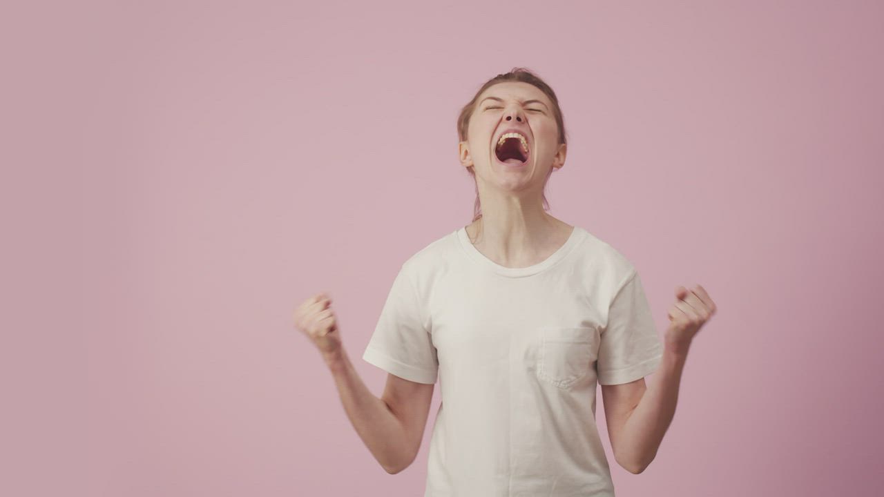 Woman screaming with rage against a pink background - Free Stock Video