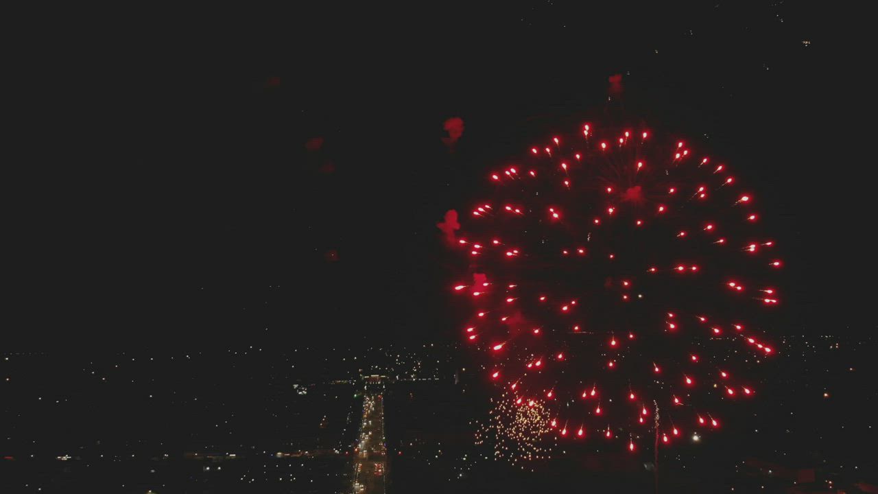 Great fireworks display blasting high over a city below - Free Stock Video
