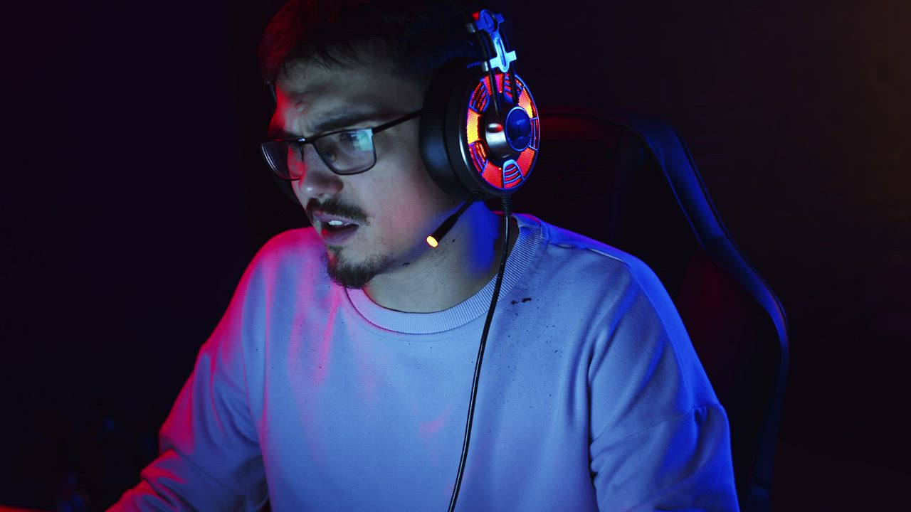 Gamer sitting at a computer screen concentrating on playing a game ...