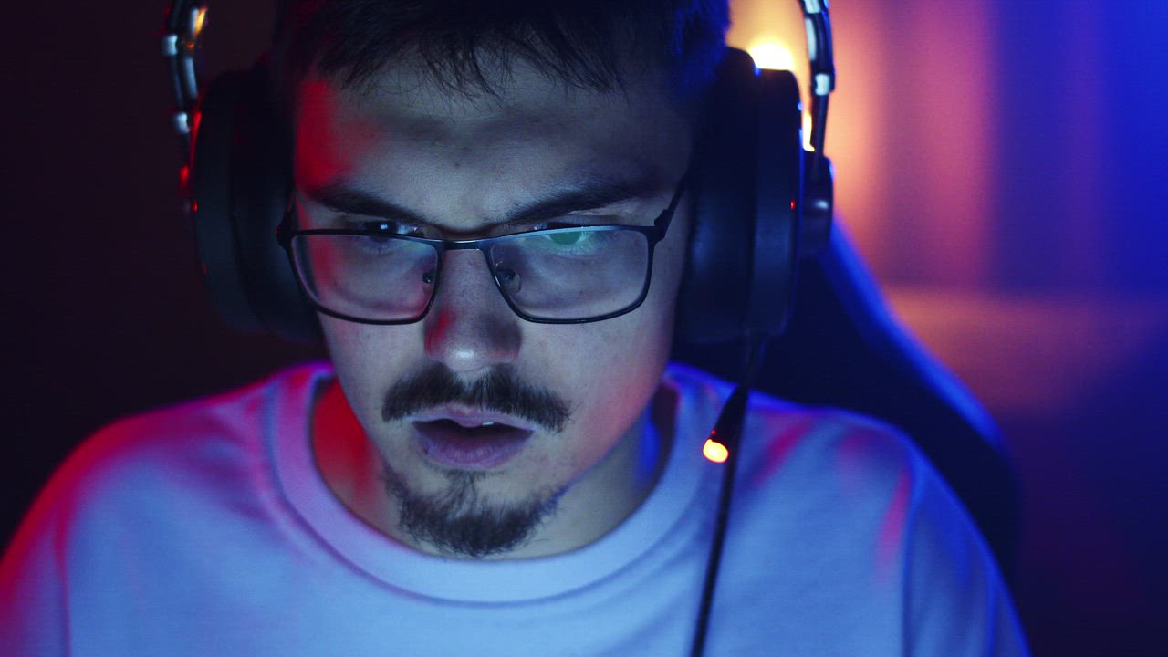 Gamer talking into a headset while gaming with friends - Free Stock Video