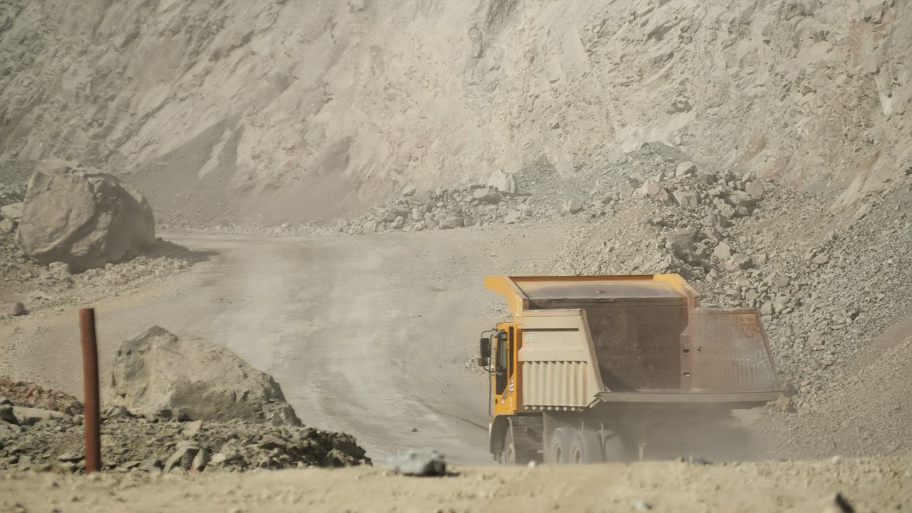 Yellow truck driving along a dusty road in a mining site - Free Stock Video