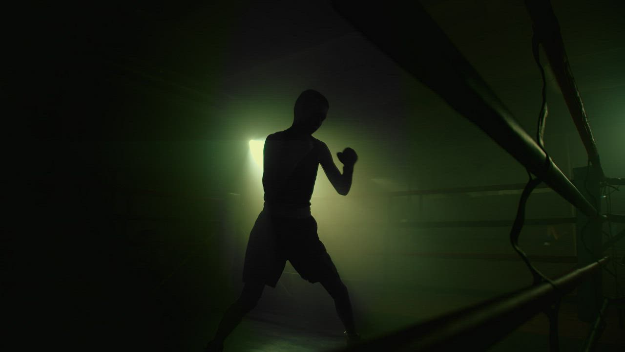 Lightweight boxer practicing in a dark boxing ring - Free Stock Video