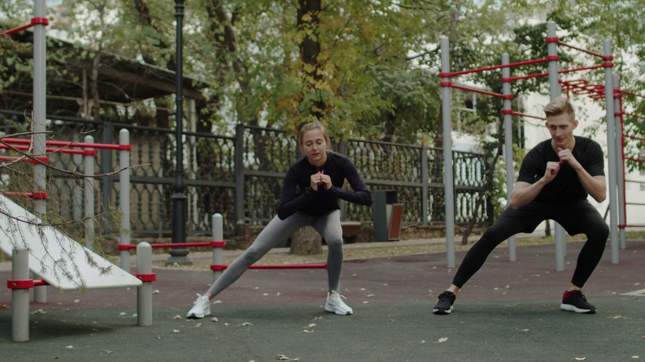 Two people doing warm up stretches in a playground - Free Stock Video