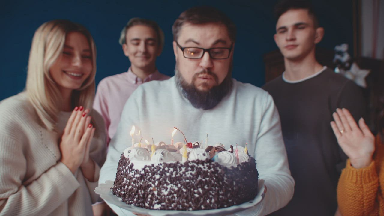 Man blowing out the candles of a birthday cake - Free Stock Video