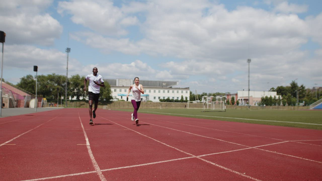 Two athletes racing a long a track share a high five - Free Stock Video