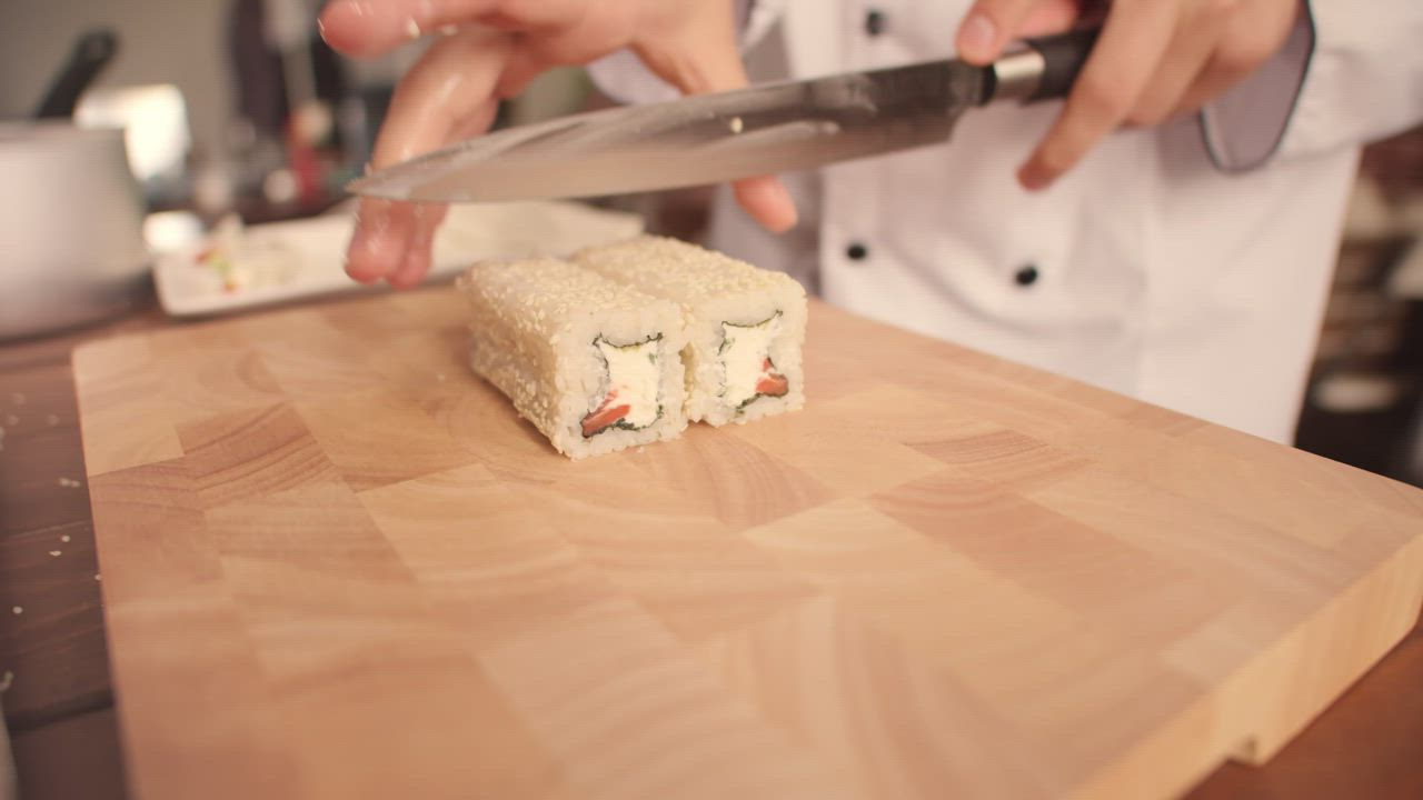 Chef chopping a roll of sushi with a sharp knife - Free Stock Video