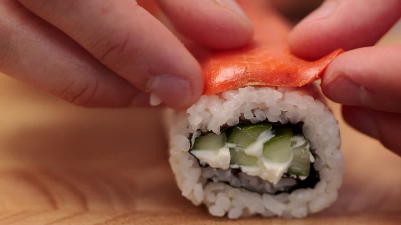 Chef removing a slice of salmon from a roll of sushi - Free Stock Video