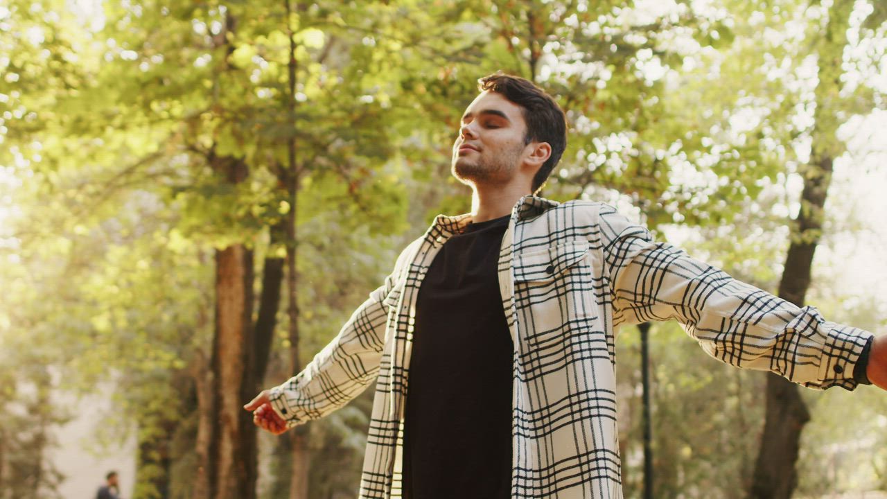 Man taking a deep breath in a sun-filled forest - Free Stock Video