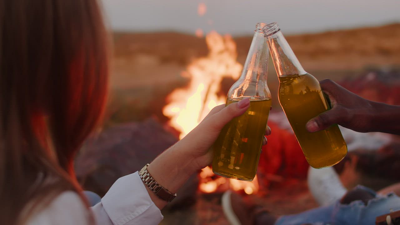 Friends sharing a beer next to a campfire - Free Stock Video