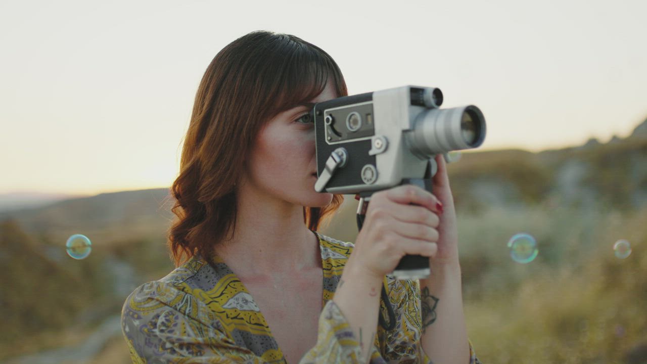 Woman holding a 8mm camera slowly turns as she films bubbles - Free ...