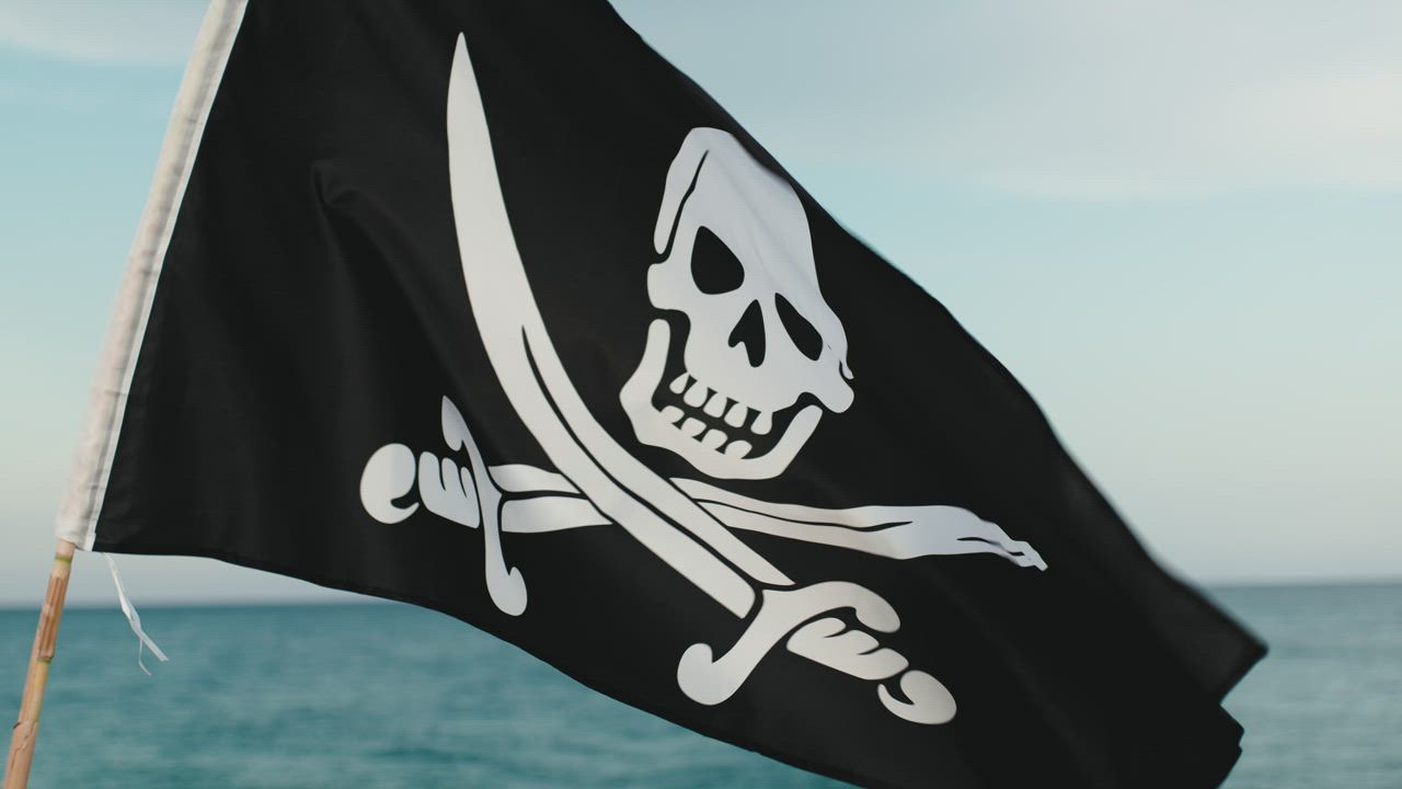Pirate flag waving in the wind on a ship mast out at sea - Free Stock Video