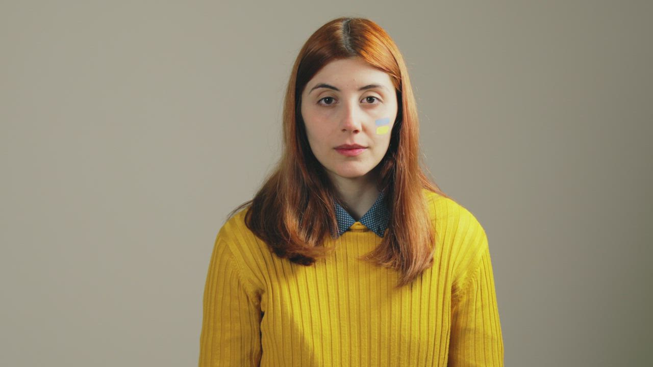 Stoic woman holding a red-painted hand to the screen - Free Stock Video