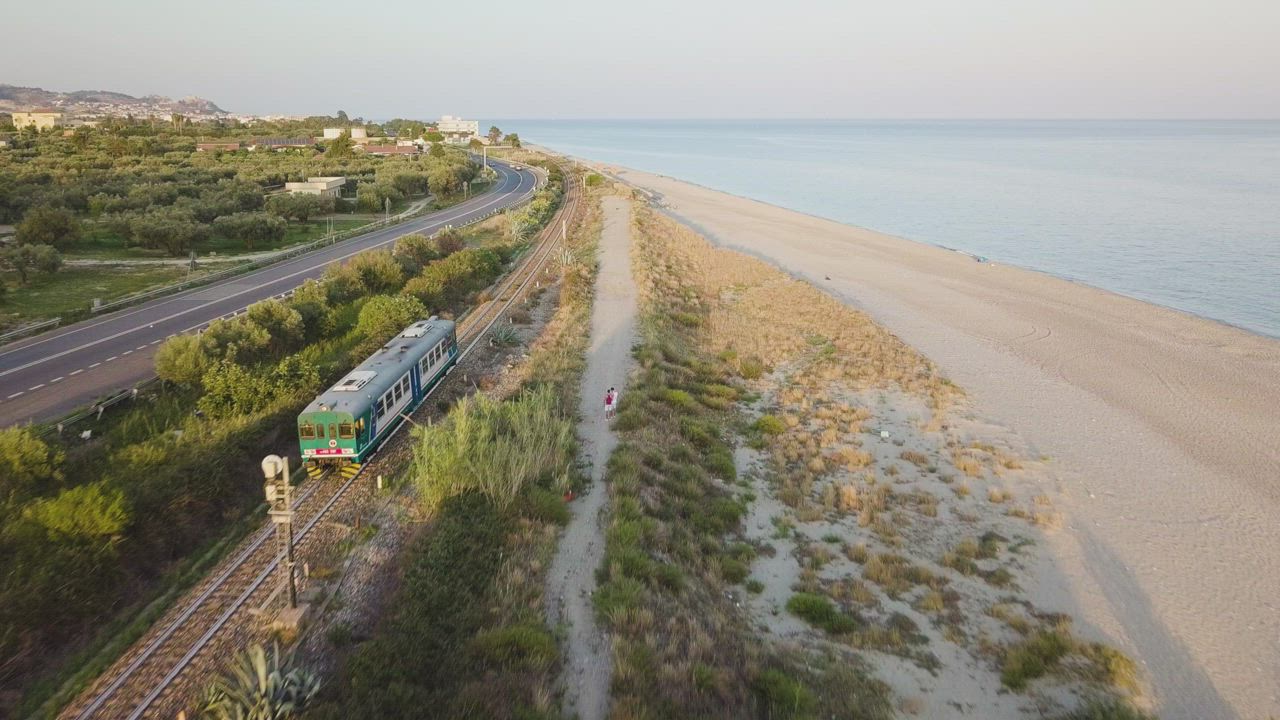 Train transits alongside the ocean at sunset - Free Stock Video
