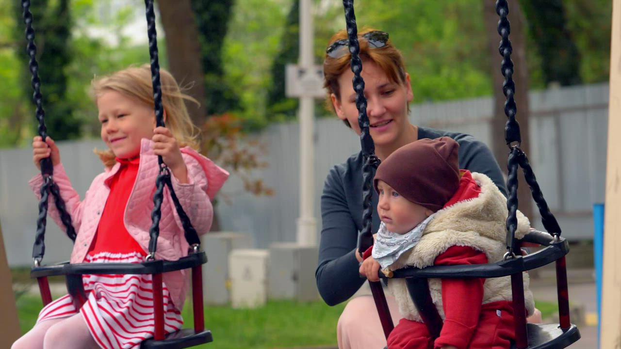 Mother pushing her children on swings in a park - Free Stock Video
