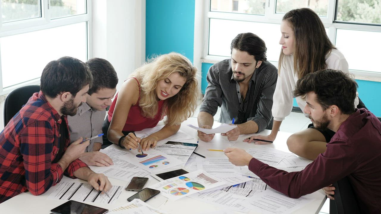 People around a desk working on a project - Free Stock Video