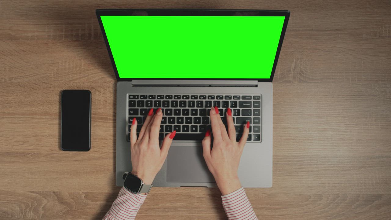 Hands typing on a keyboard with a green screen laptop - Free Stock Video