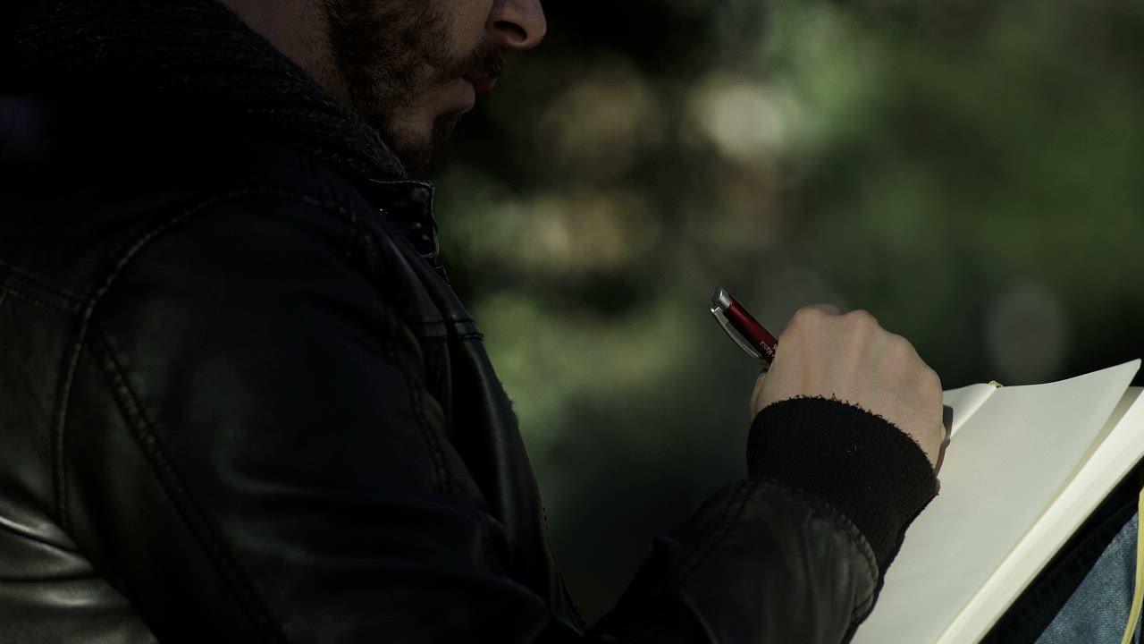 Close up of a man writing in a notebook - Free Stock Video