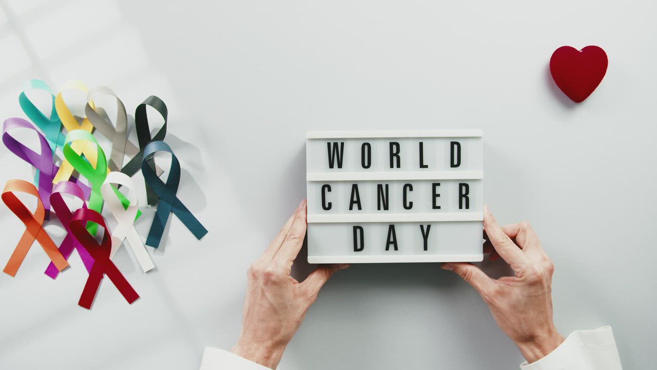 Hands placing a world cancer awareness day sign on a white background ...