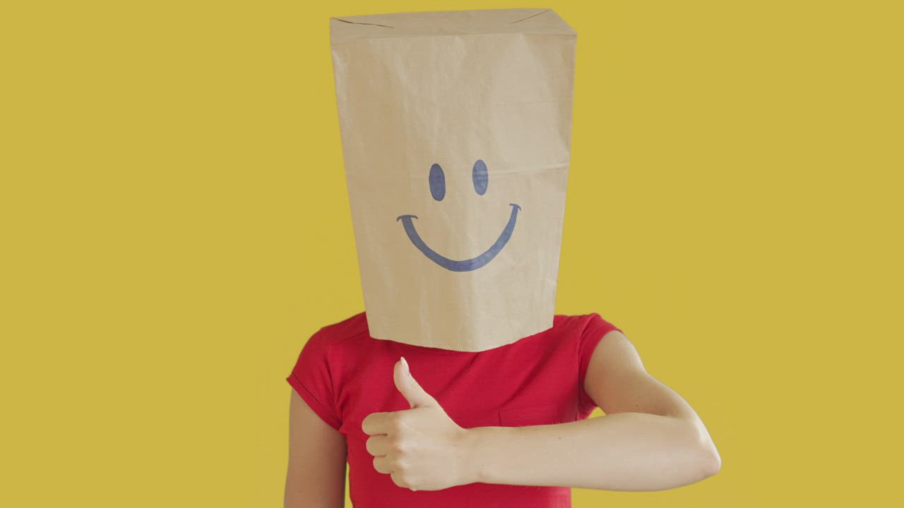Woman with a smiley bag on her head doing thumbs up - Free Stock Video