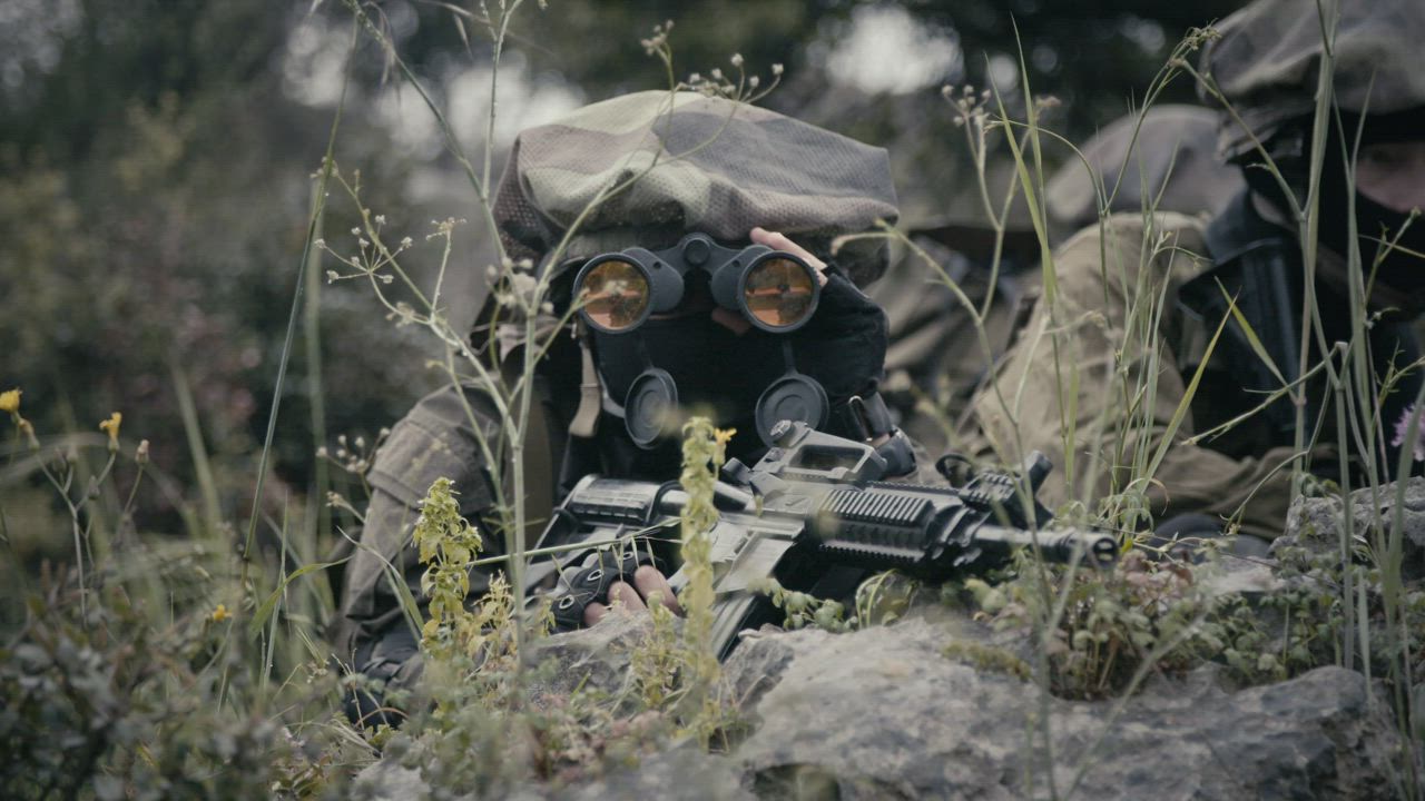 Soldiers hiding behind the bushes during surveillance using binoculars ...