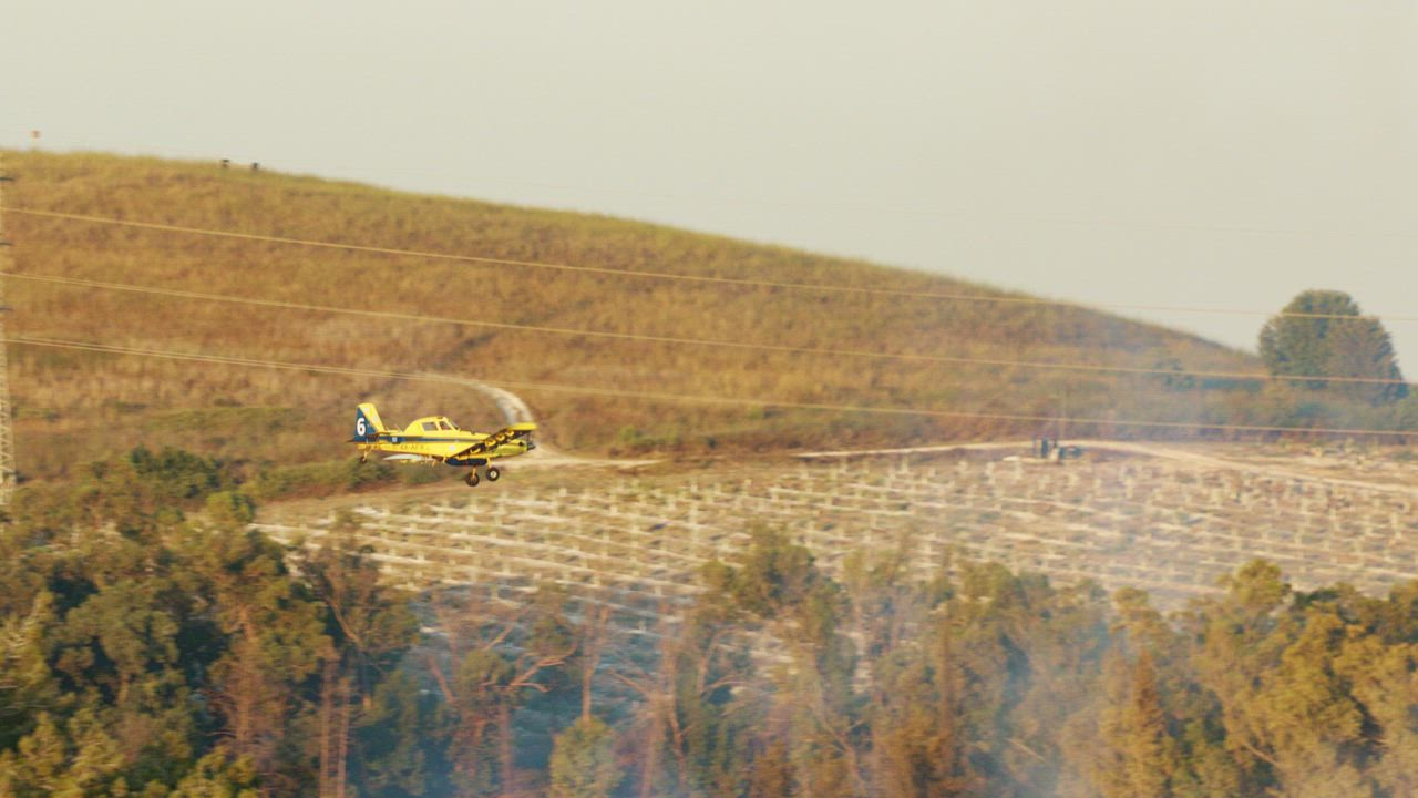 Firefighter plane drops fire retardant on a forest fire in the hills ...