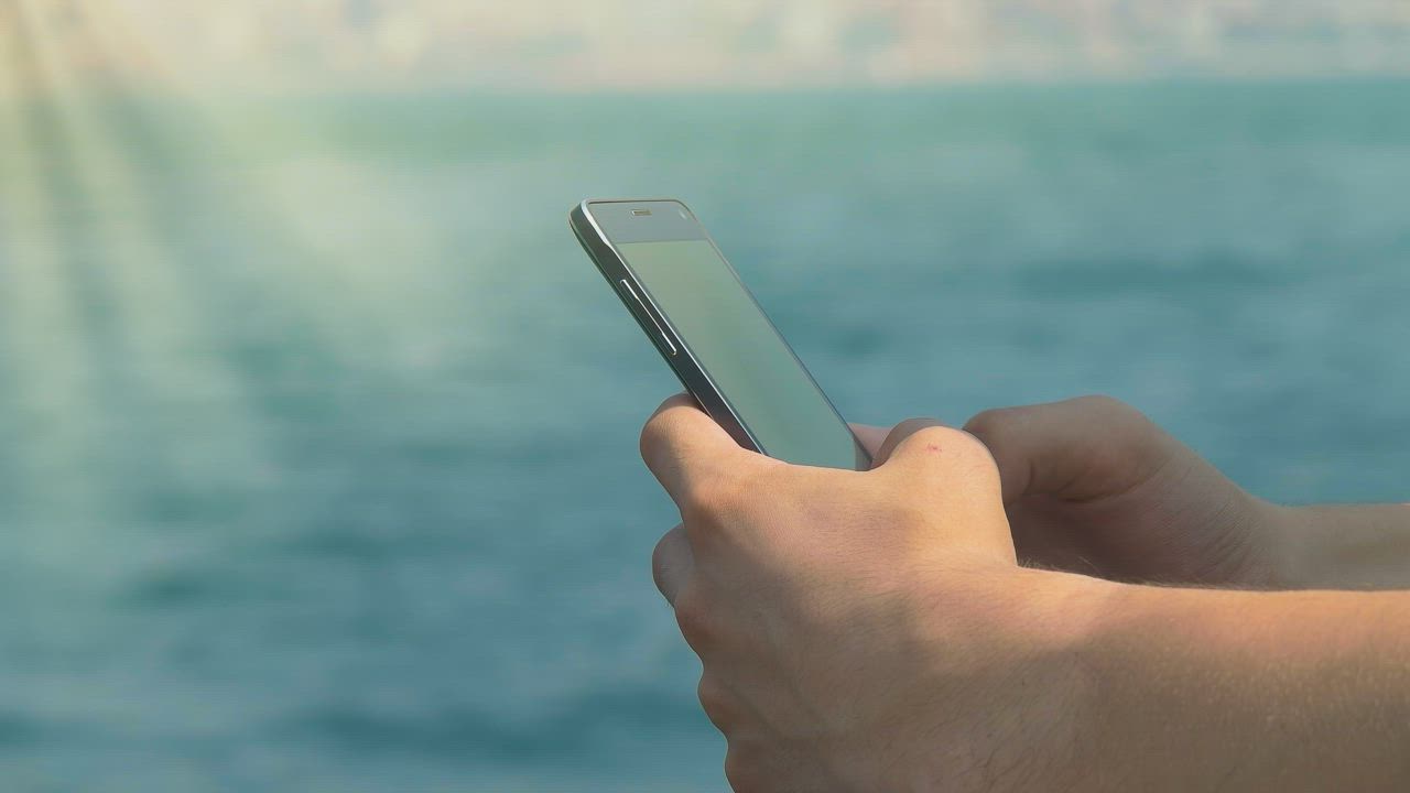 Man typing on a phone on a pier - Free Stock Video