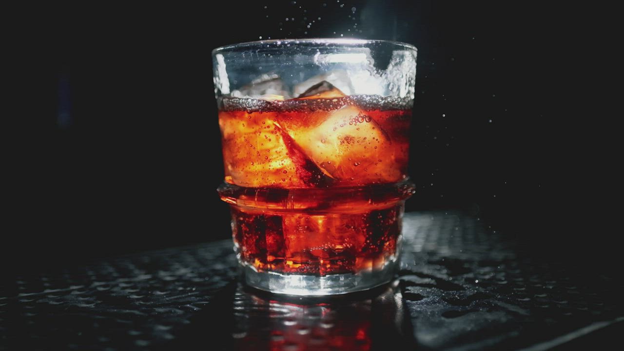 Mixing cola with ice cubes in a glass - Free Stock Video