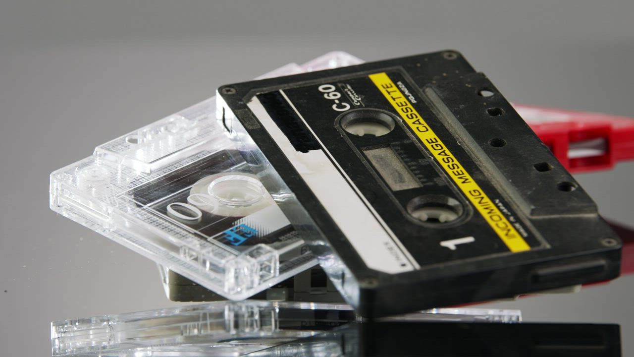 Audio cassettes rotating on a reflective surface - Free Stock Video