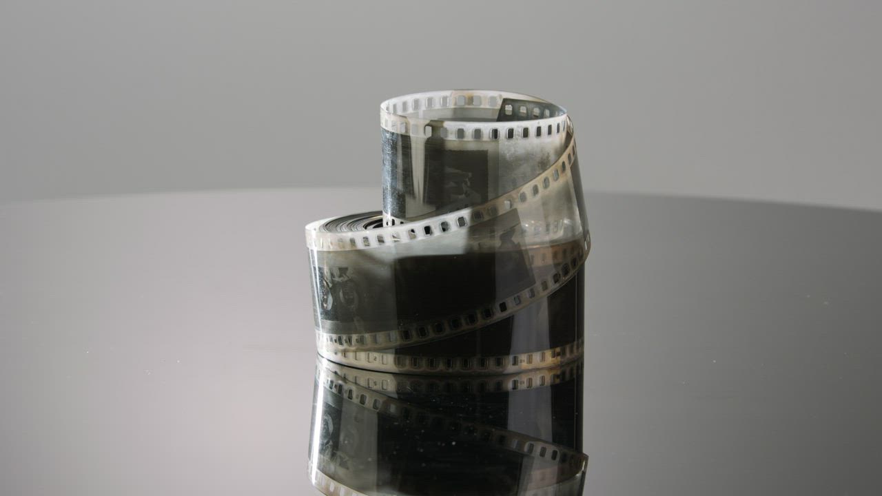 35mm film negative rotating on a reflective surface - Free Stock Video