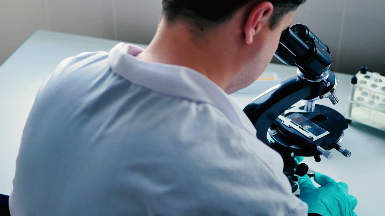 Scientist observing through a microscope - Free Stock Video