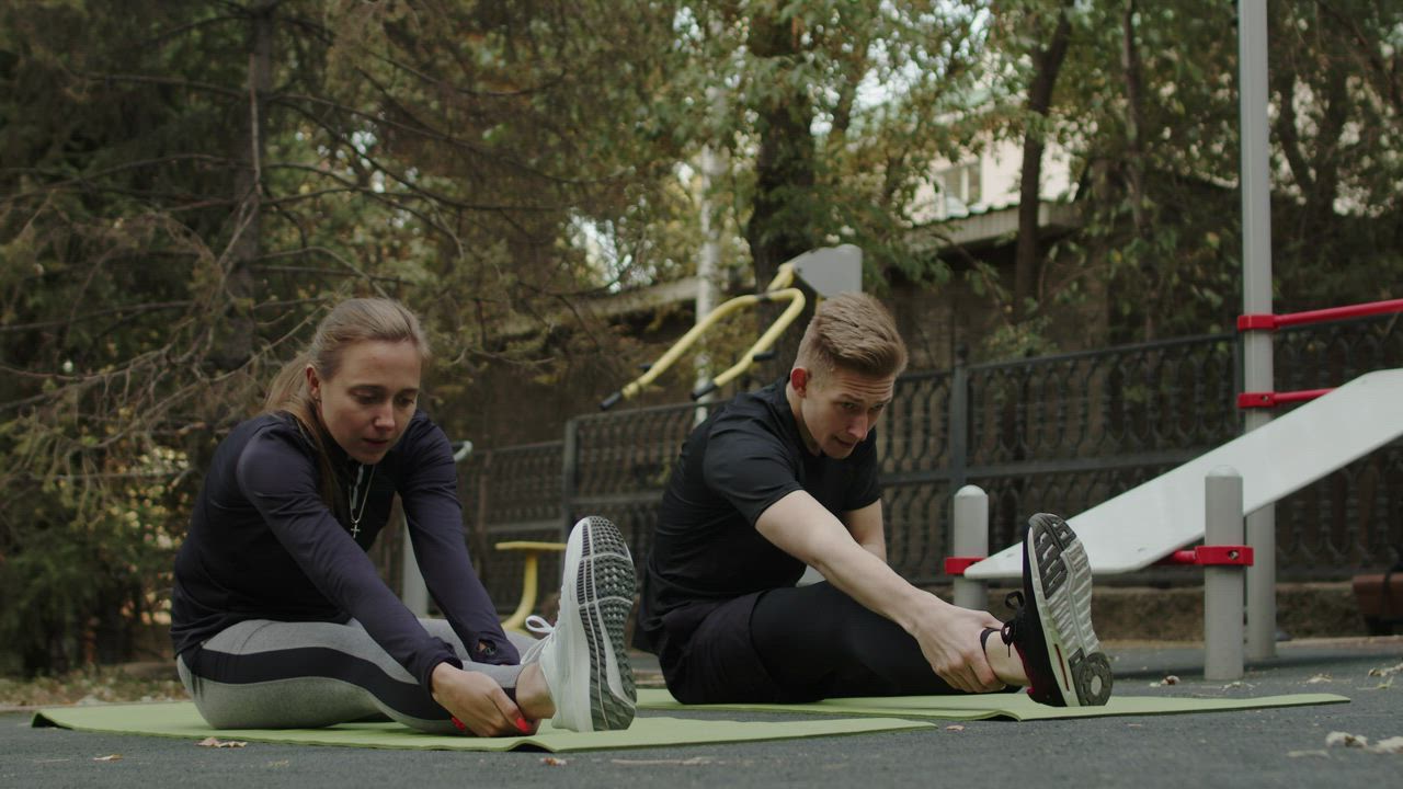 Young woman stretching with her trainer before a workout - Free Stock Video