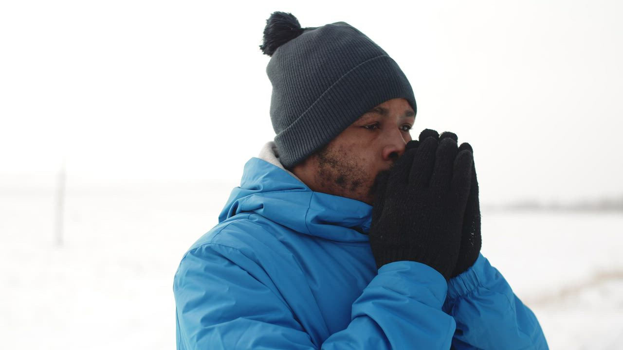 Man blowing air into his cupped hands to warm up in the cold - Free Stock Video