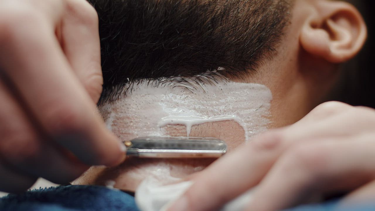 Close up of a barber shaving a client's beard - Free Stock Video
