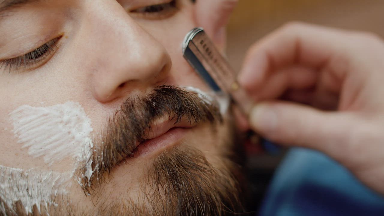 Close up of a razor blade cleaning a man's mustache - Free Stock Video