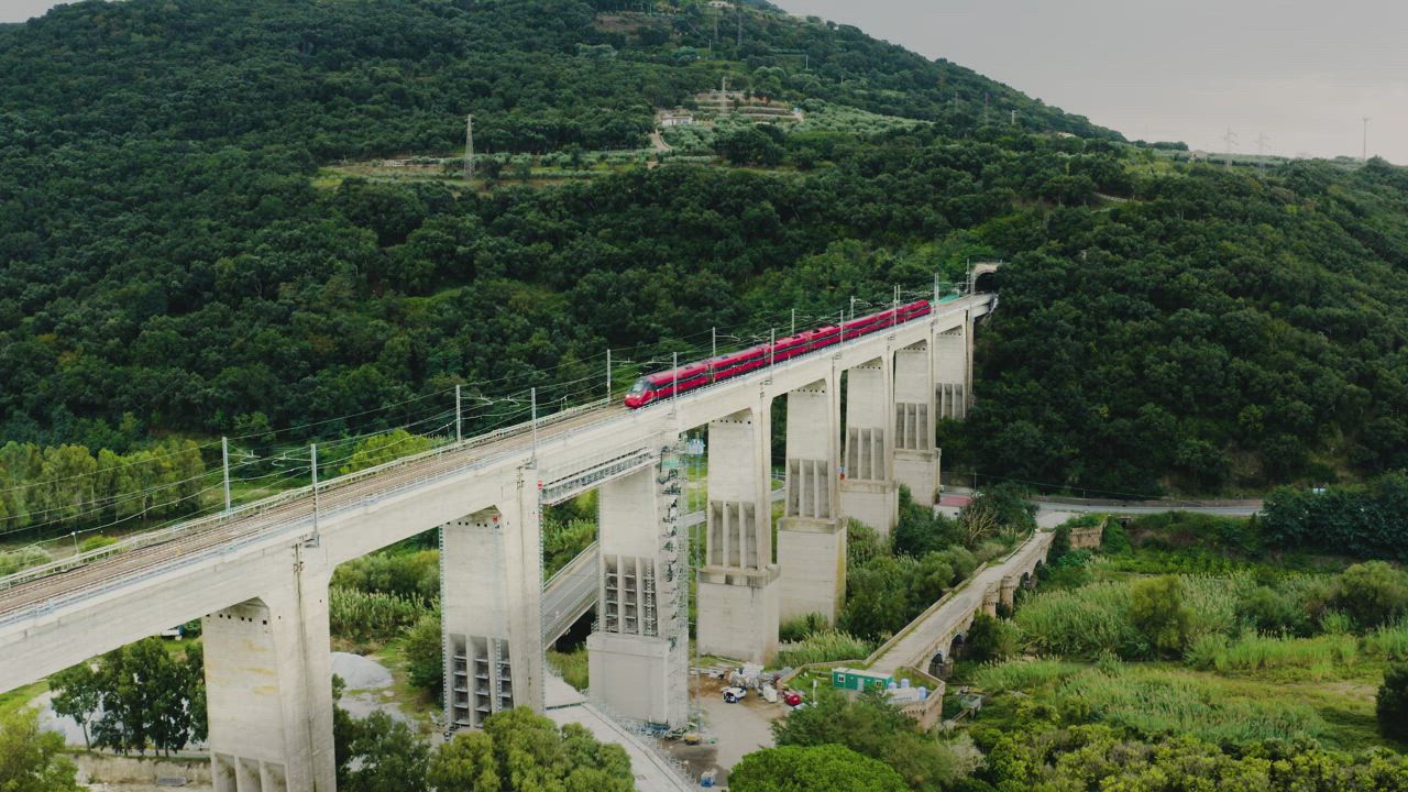 Passenger train passing over a high bridge in the middle of mountains ...