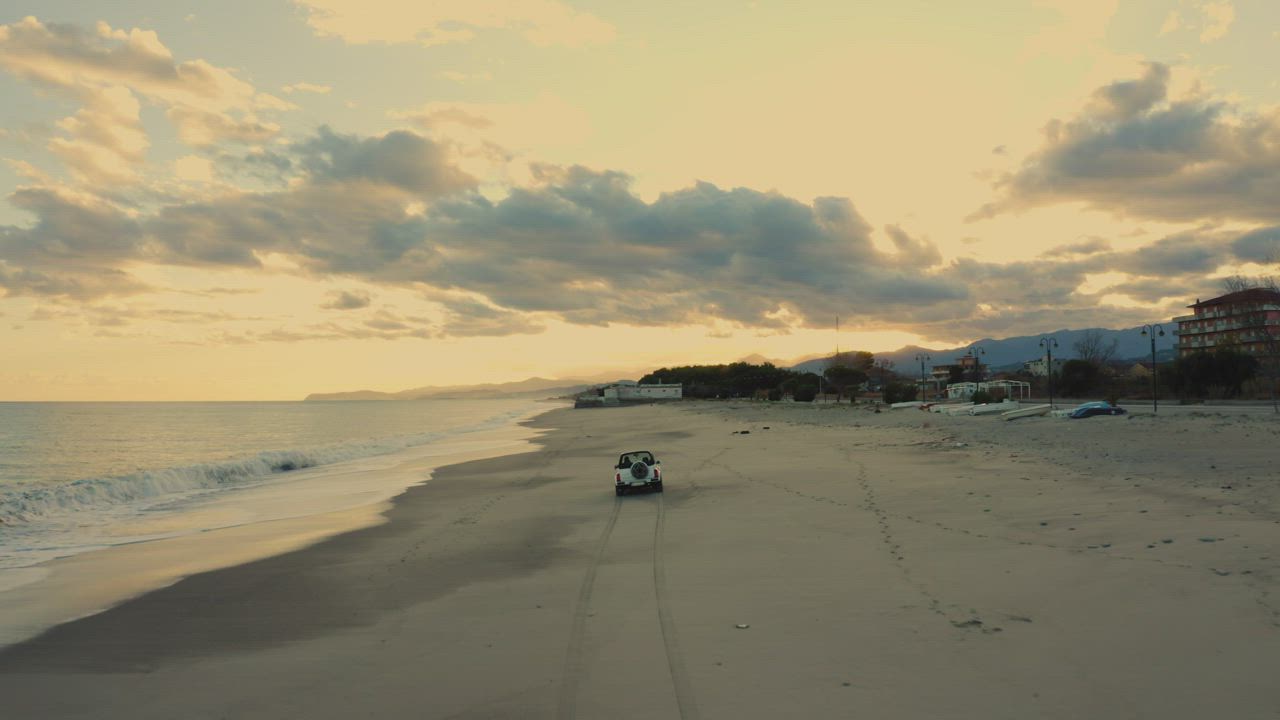 Car driving along the beach at sunset - Free Stock Video