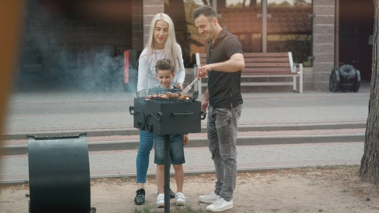 Happy family cooking grill meat outdoors - Free Stock Video