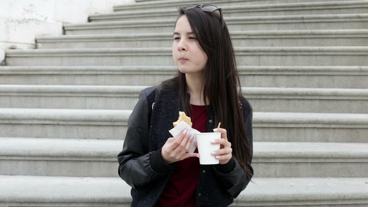 Woman sitting on steps eating a sandwich - Free Stock Video