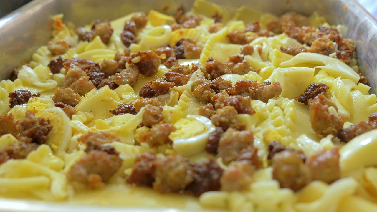 Sauce being ladled over lasagne in a ceramic dish - Free Stock Video