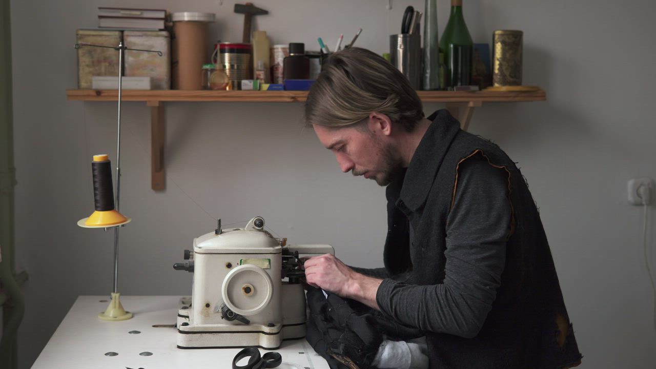 Man using a sewing machine to mend an item of clothes - Free Stock Video