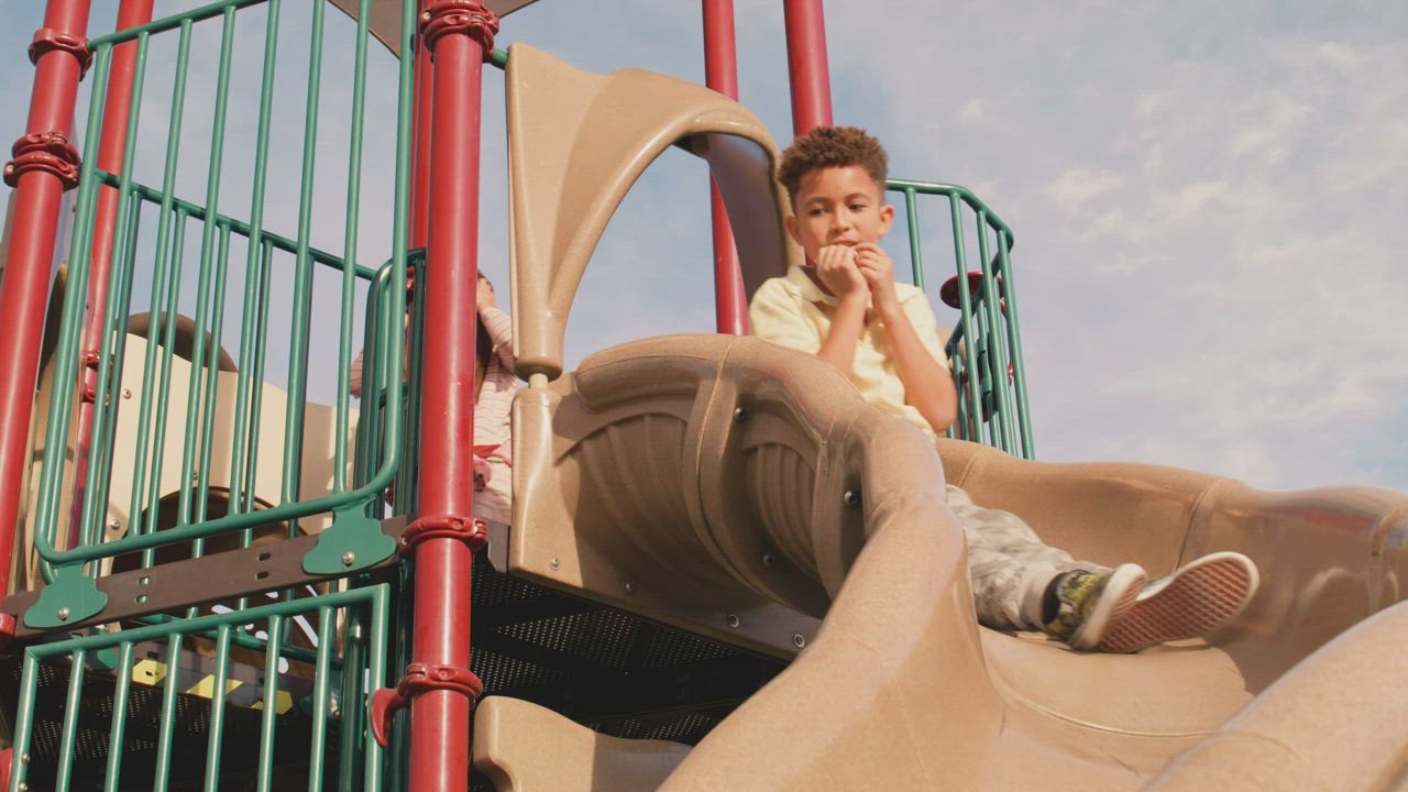 Children sliding down a slide in a park - Free Stock Video